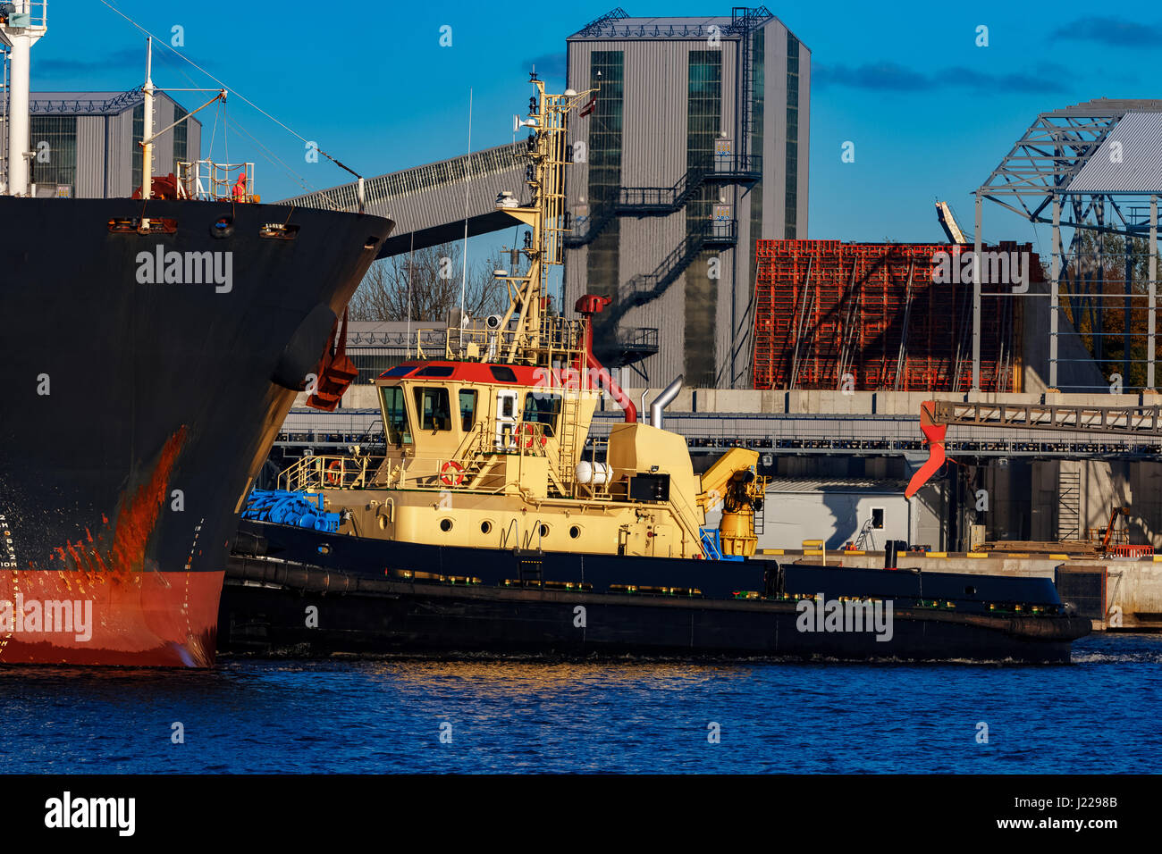 Black cargo ship mooring at the port with tug ship support Stock Photo ...