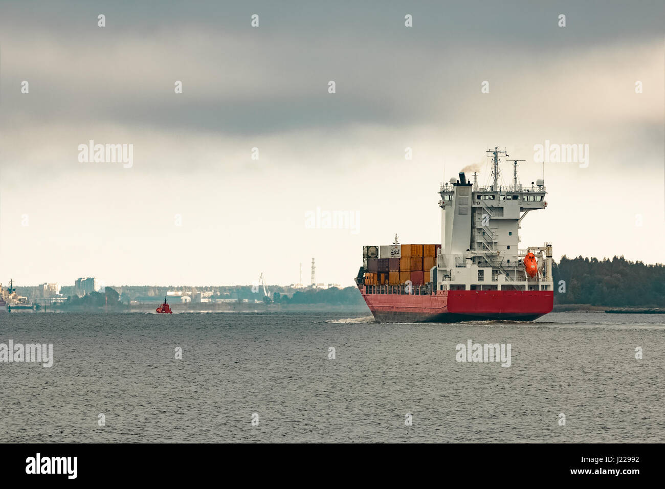 Red cargo container ship entering the port of Riga in cloudy day Stock ...