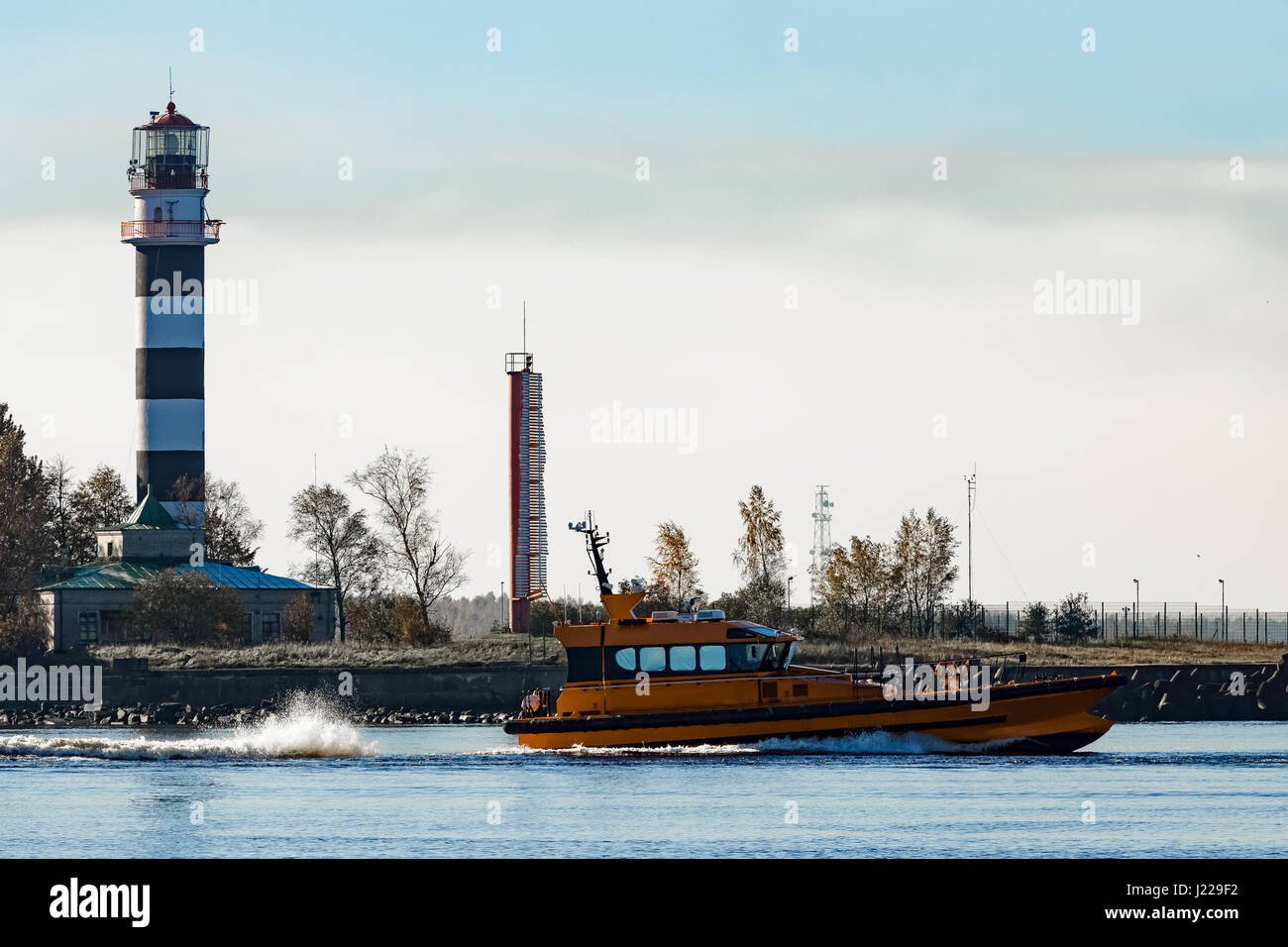 Orange pilot ship sailing past the lighthouse in Riga Stock Photo - Alamy