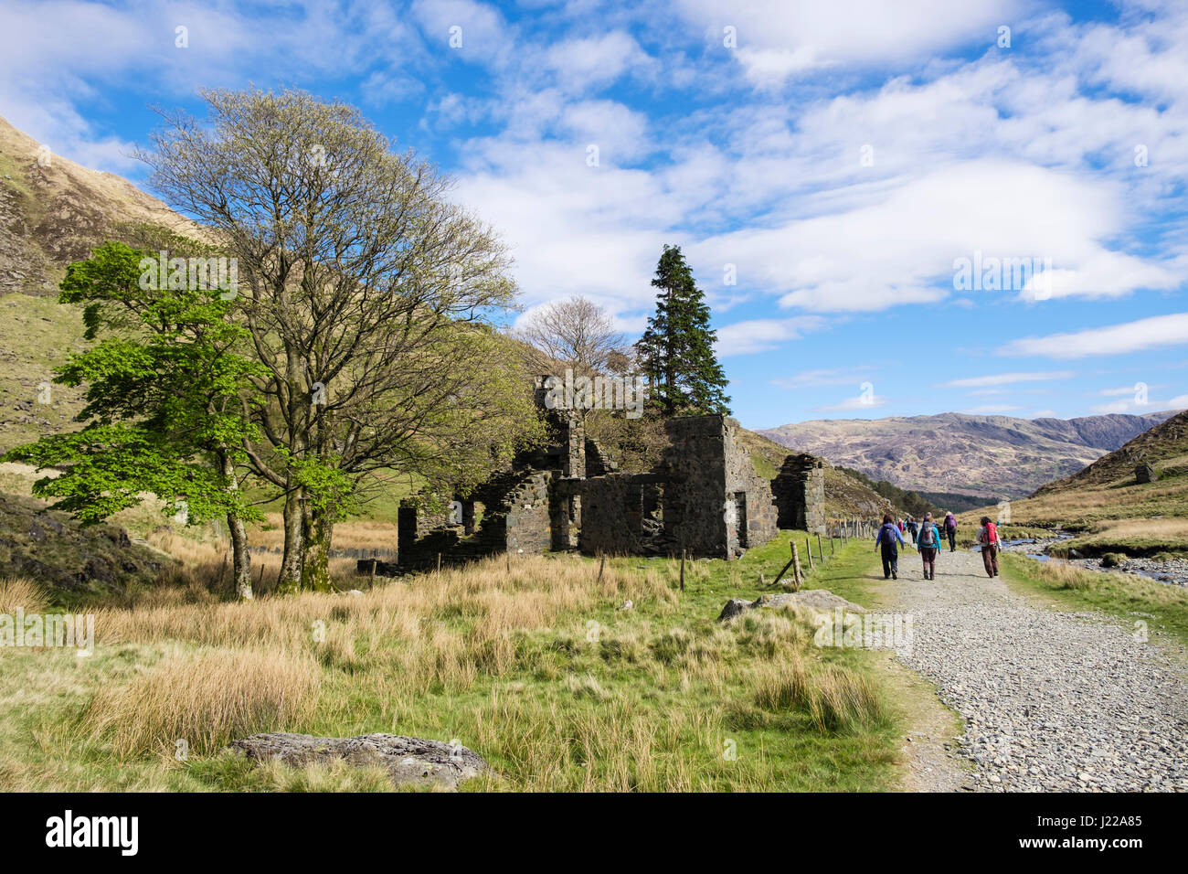 Hikers hiking on the Watkin path passing old ruins in mountains of ...