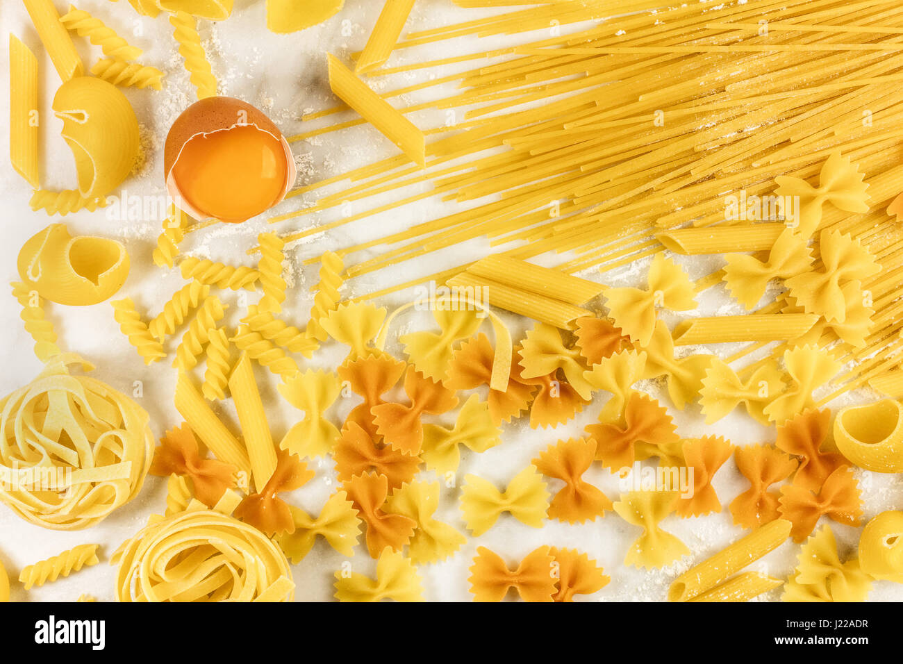 An overhead photo of various types of pasta on a white marble table ...