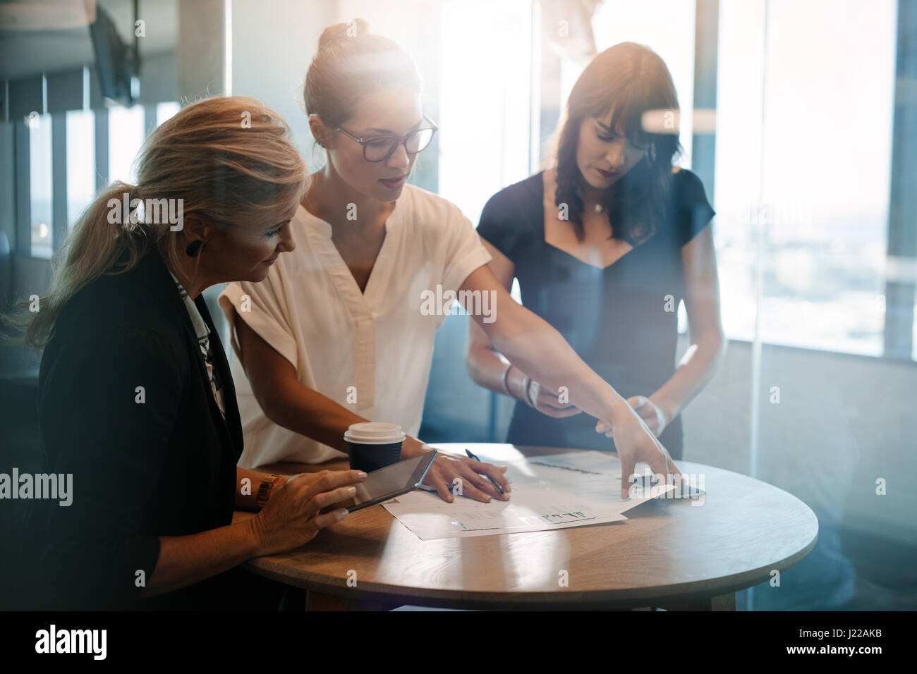 Three businesswomen discussing over documents on table. Female ...