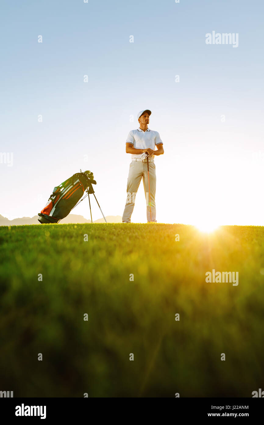 Low angle shot of professional golfer standing on field at sunset ...