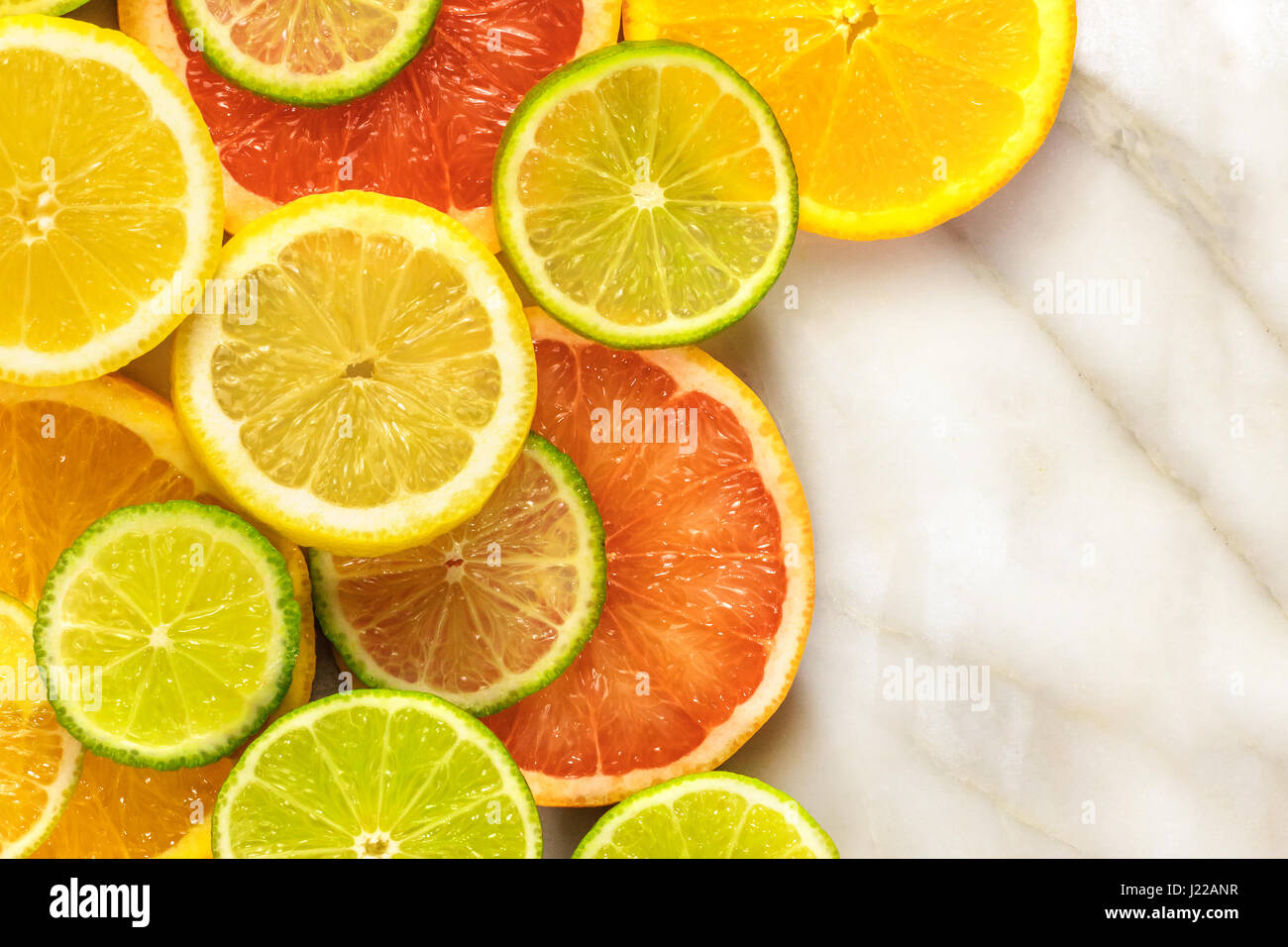 Vibrant juicy citrus fruits on a white marble texture with copy space ...