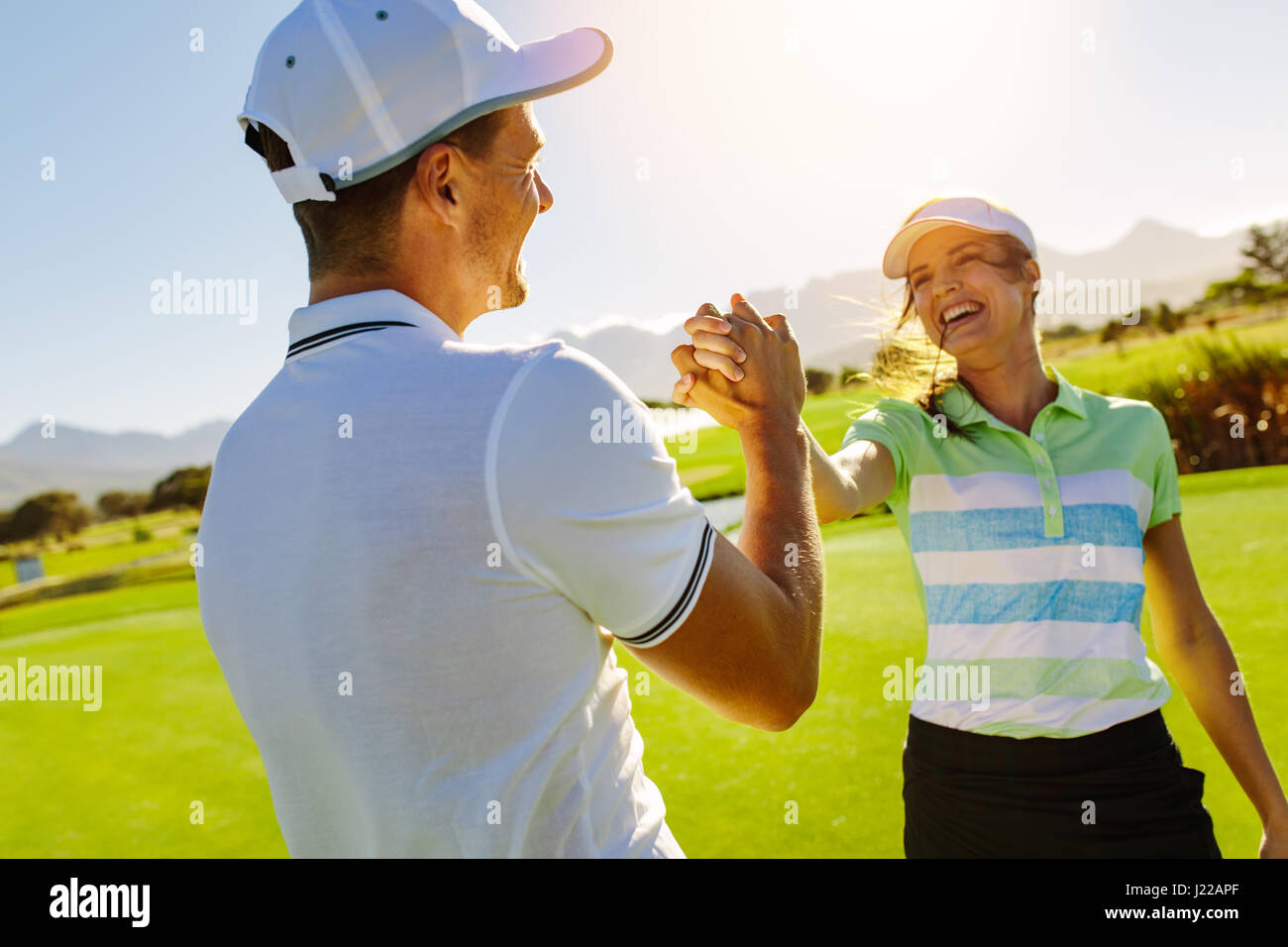 Happy male and female friends shaking hands at golf course after the ...