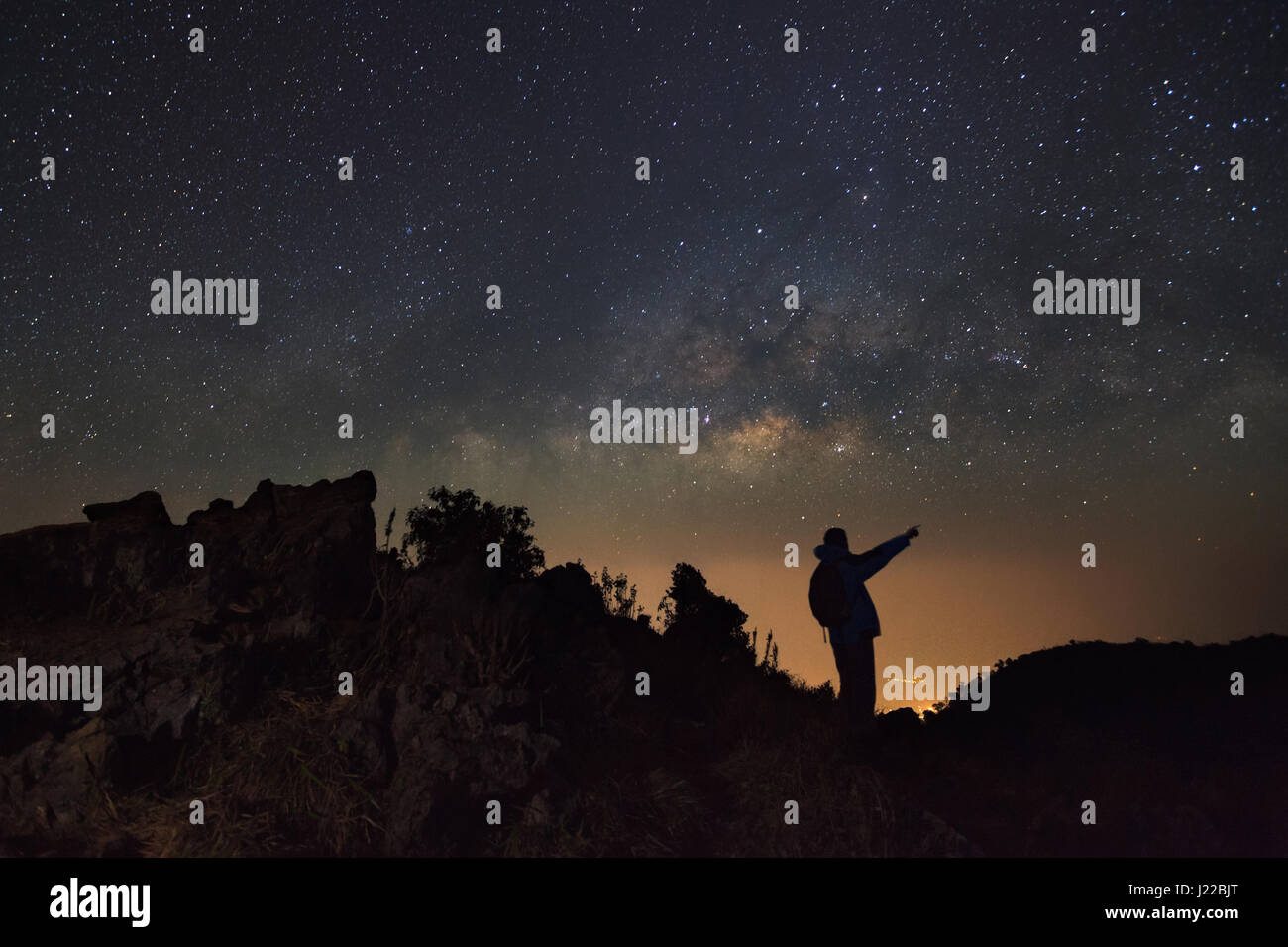 A Man is standing next to the milky way galaxy pointing on a bright ...