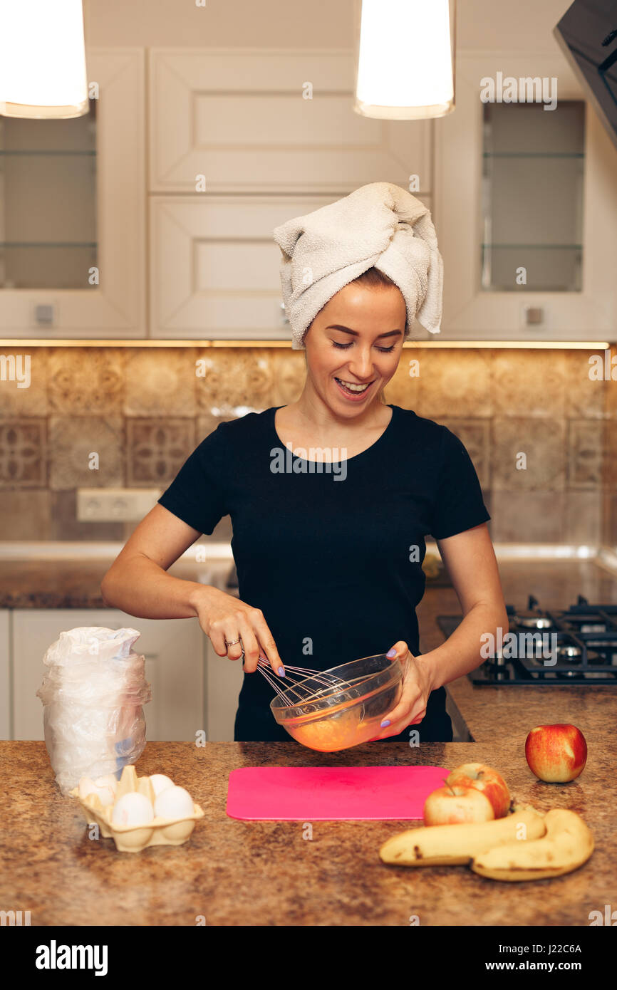 Beautiful young woman smiling while baking in kitchen Stock Photo - Alamy