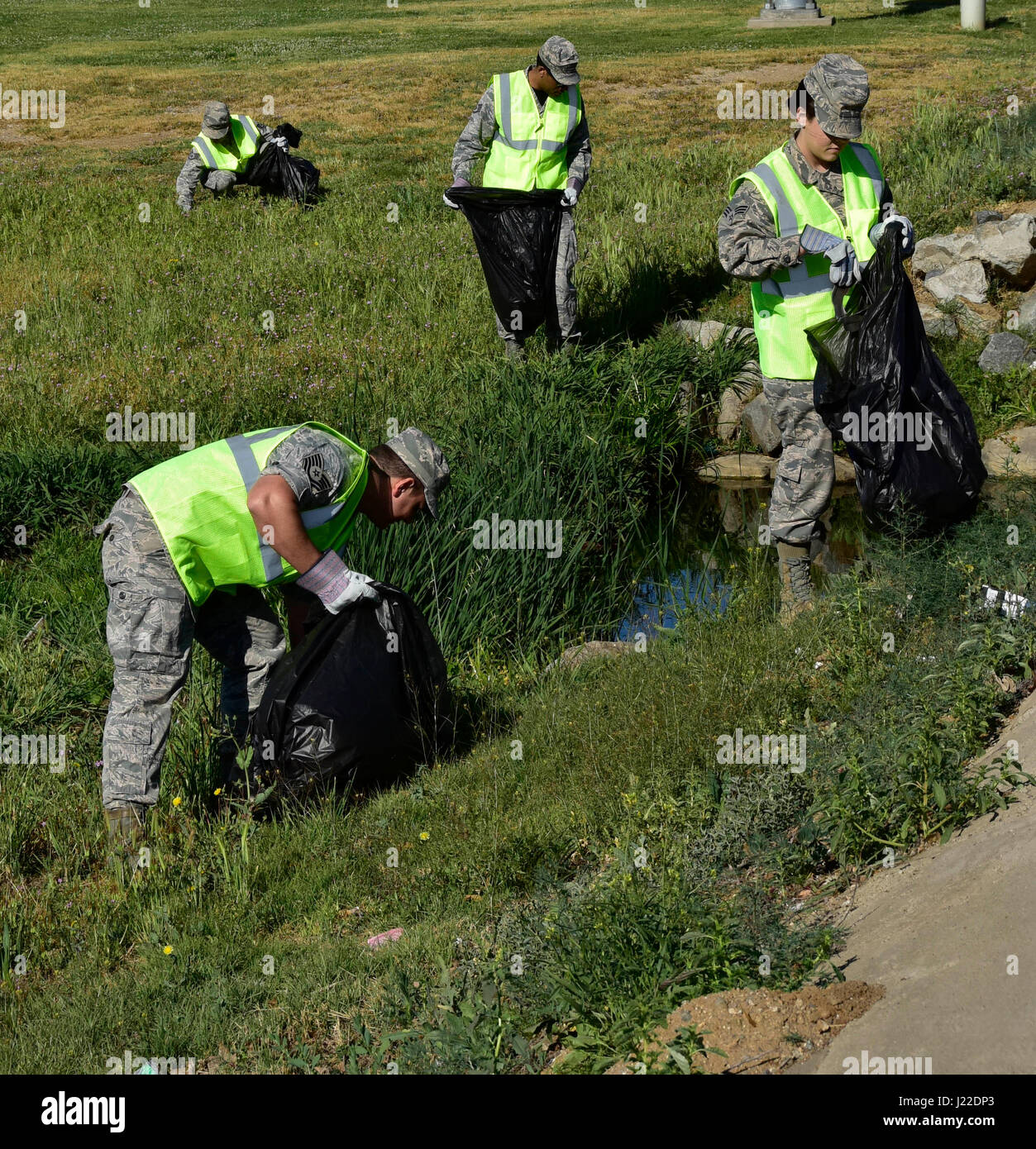 Airmen from the 163d Attack Wing pick up trash along the fence line ...