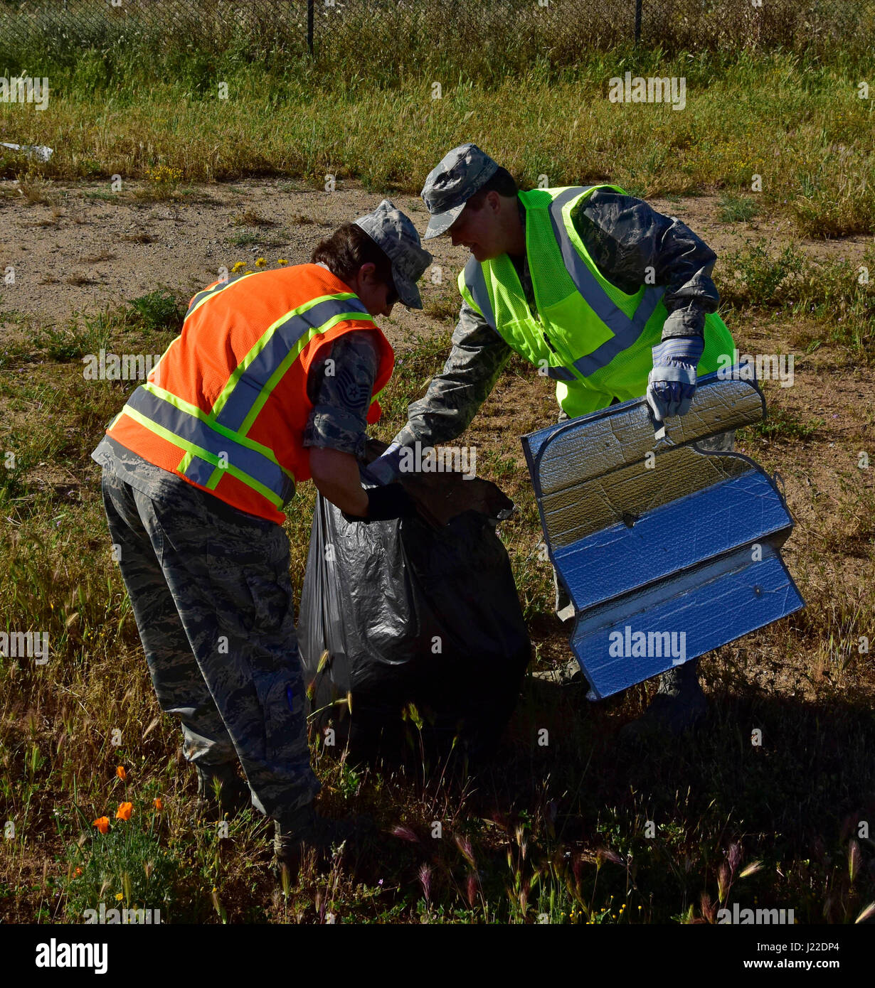Airmen from the 163d Attack Wing pick up trash along the fence line ...