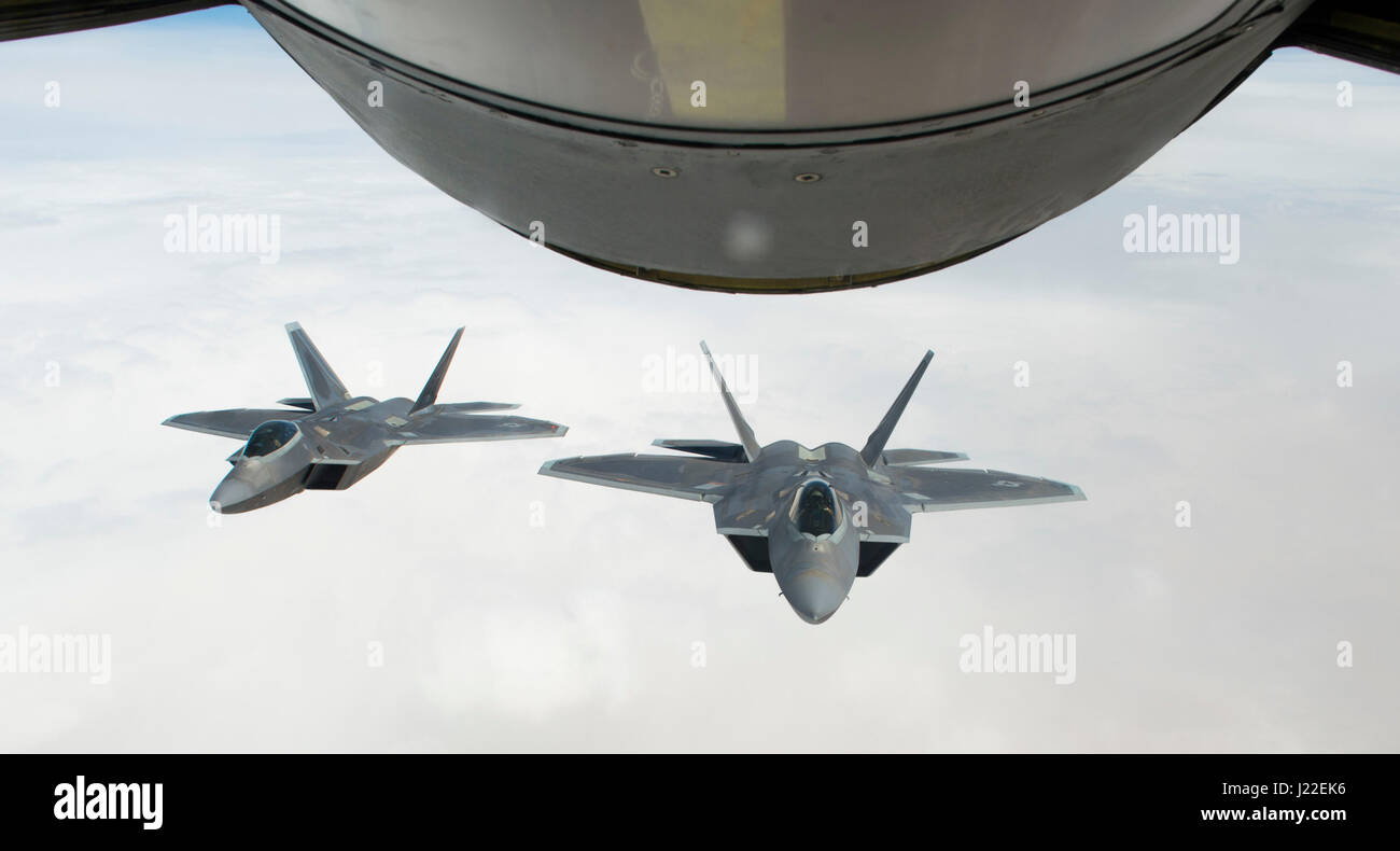 Two U.S. Air Force F-22 fly in formation behind a U.S. Air Force KC-135 ...