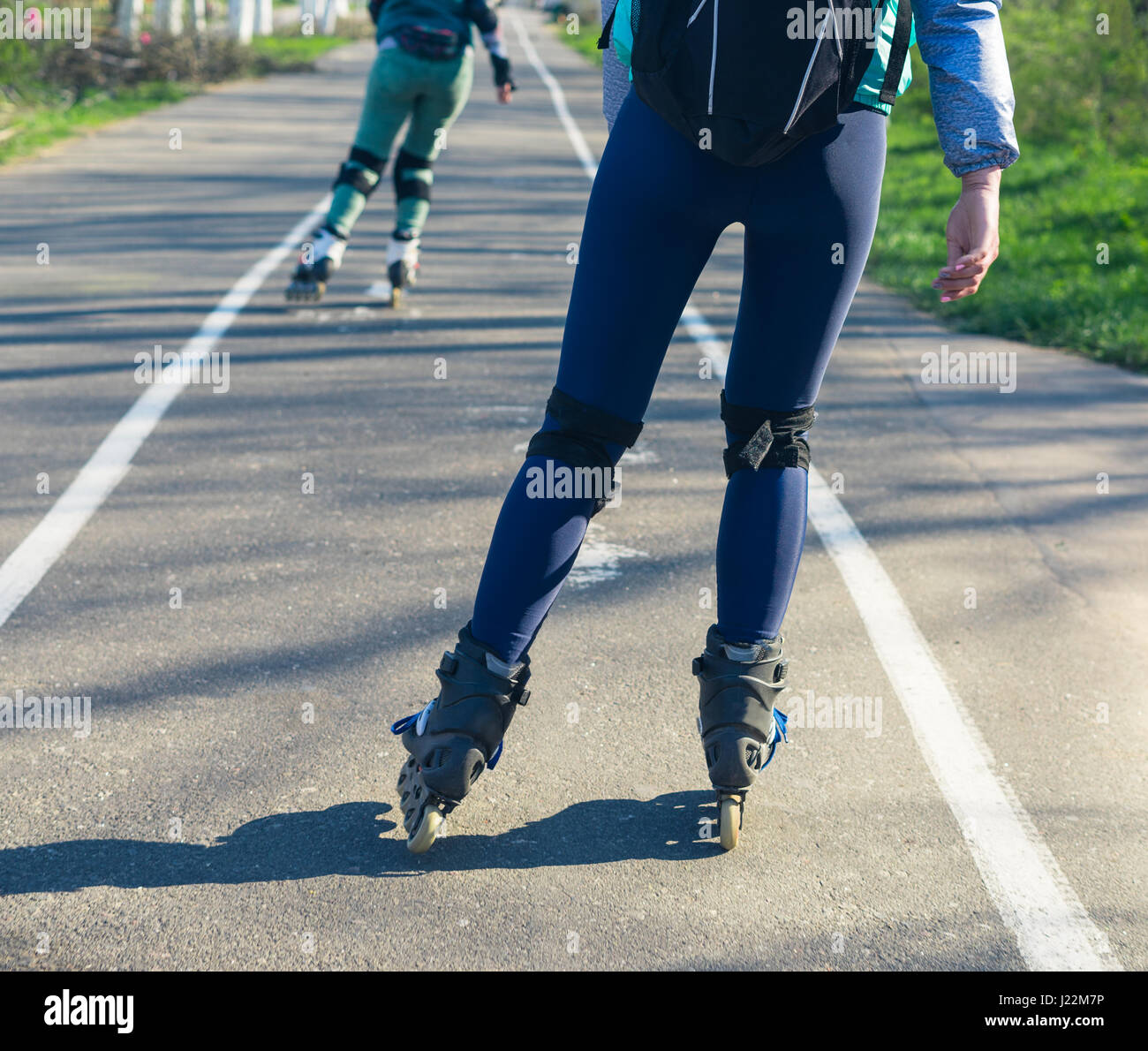 Two girls on roller skates ride along the road next to each other Stock ...