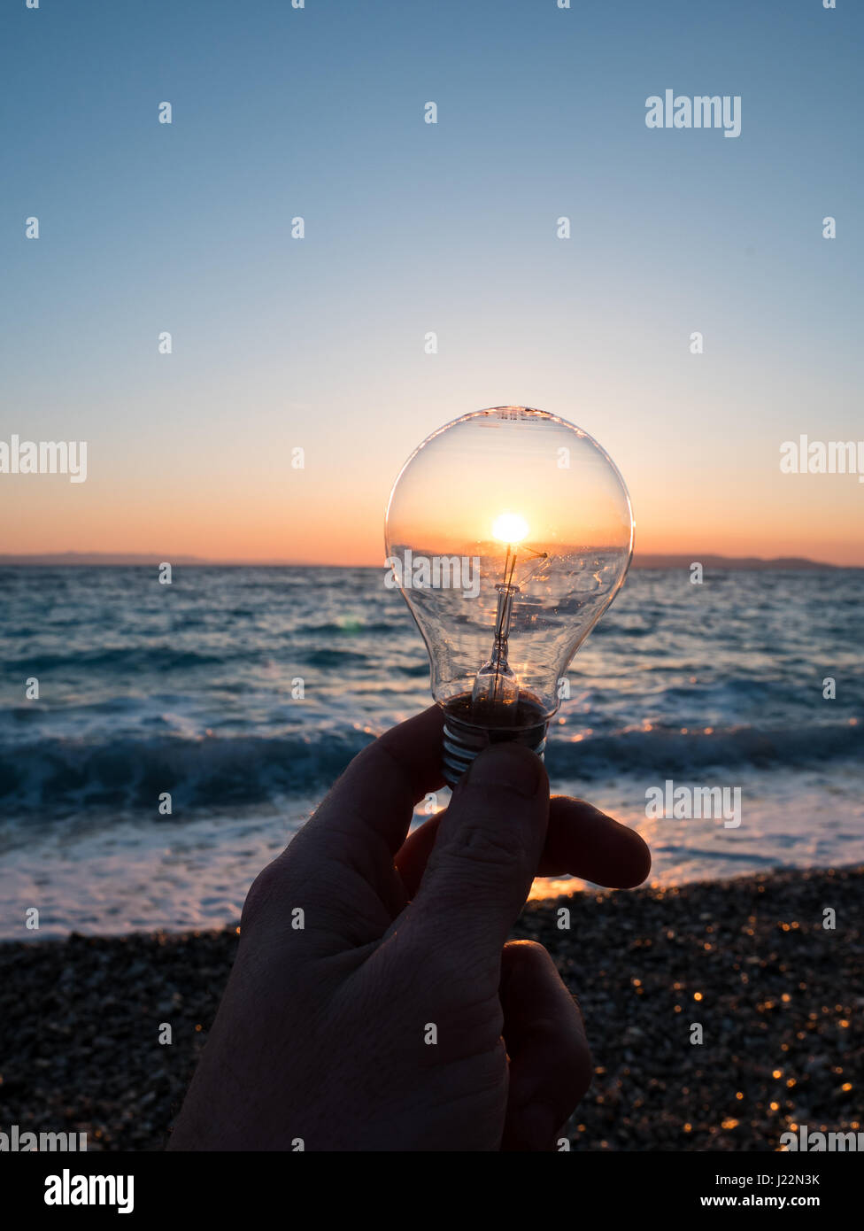 Man with light bulb against sun at beach concept Stock Photo - Alamy
