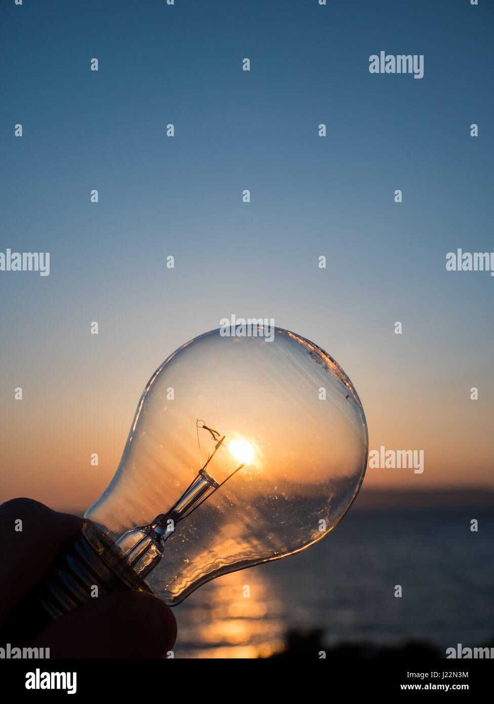 Man holding light bulb at sunset, green energy concept Stock Photo - Alamy