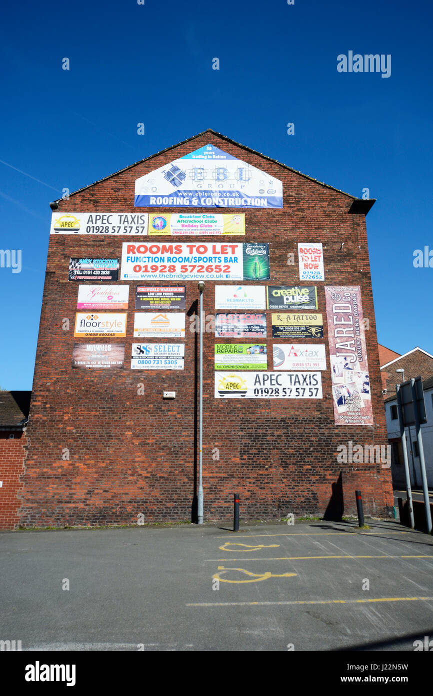 Banners advertising local businesses attached to end wall of a building ...