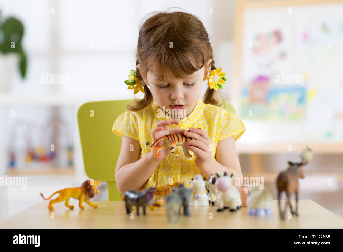 child playing with animal toys at table in kindergarten or home Stock ...
