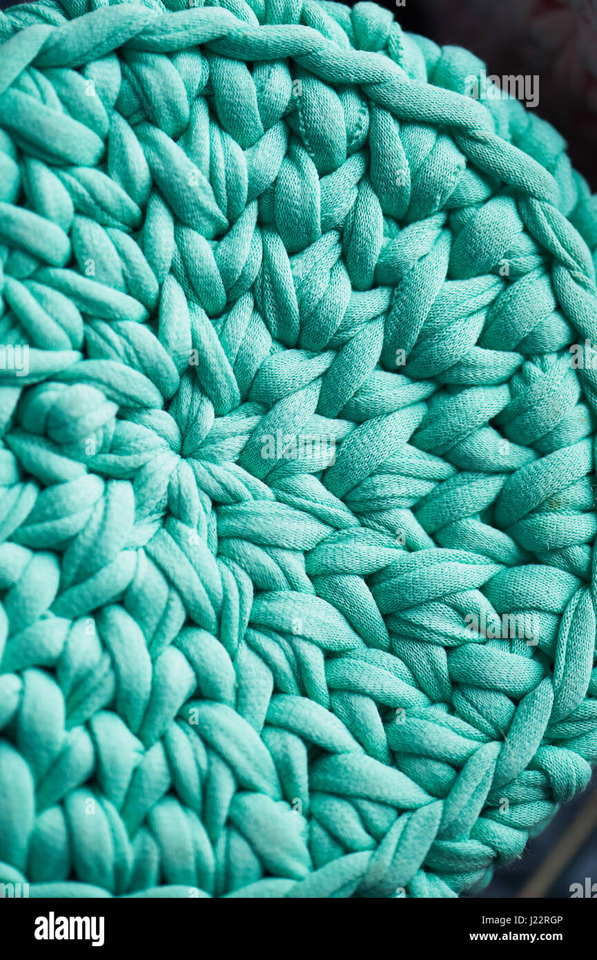 Texture. Turquoise crochet in a circle of knitted yarn fabric. Close ...