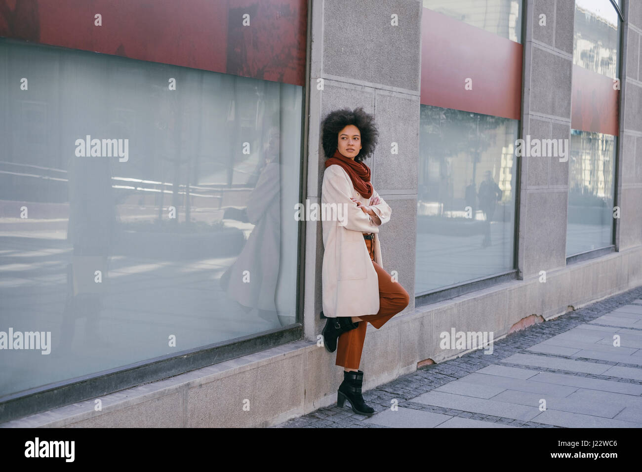 Woman leaning against a building looking sideways Stock Photo - Alamy