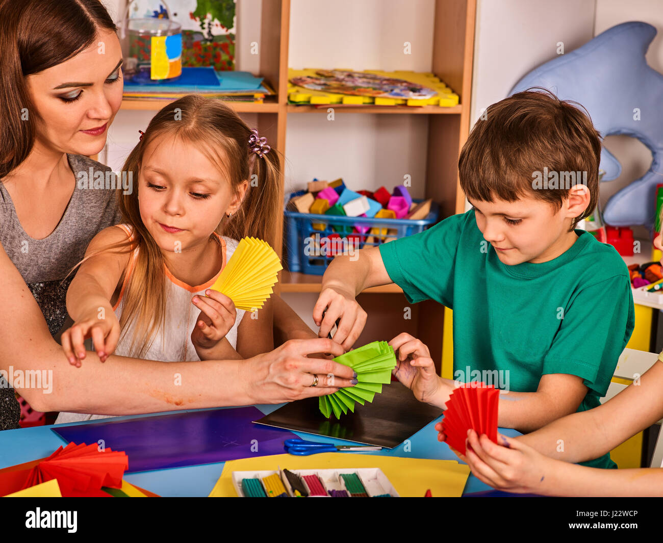 Preschool scissors in kids hands cutting color paper with teacher Stock ...
