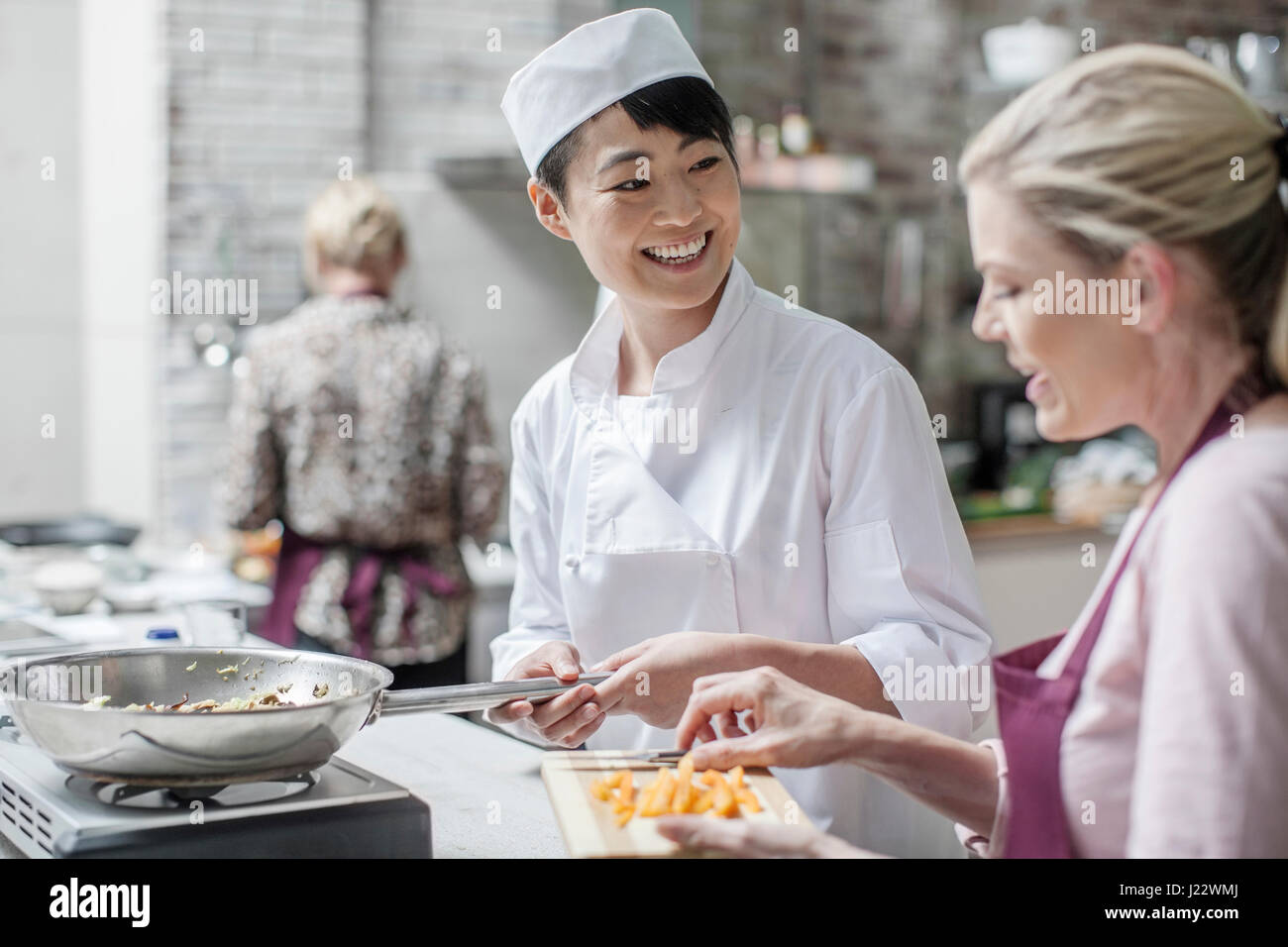 Female chef smiling at student in cooking class Stock Photo - Alamy