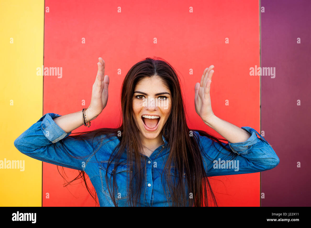 Portrait of screaming young woman in front of colourful wall Stock ...