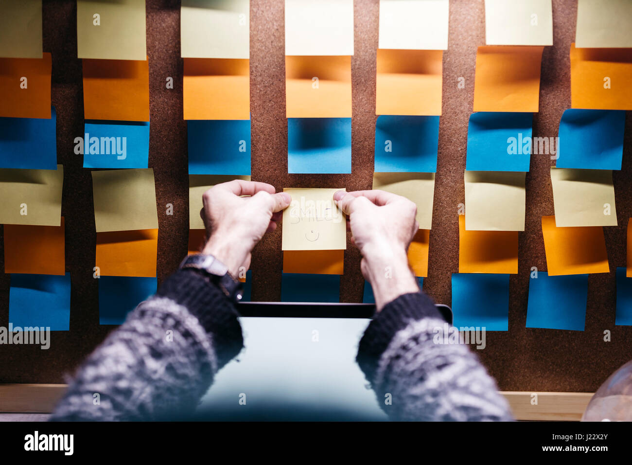 Man's hands placing a reminder on pinboard Stock Photo - Alamy