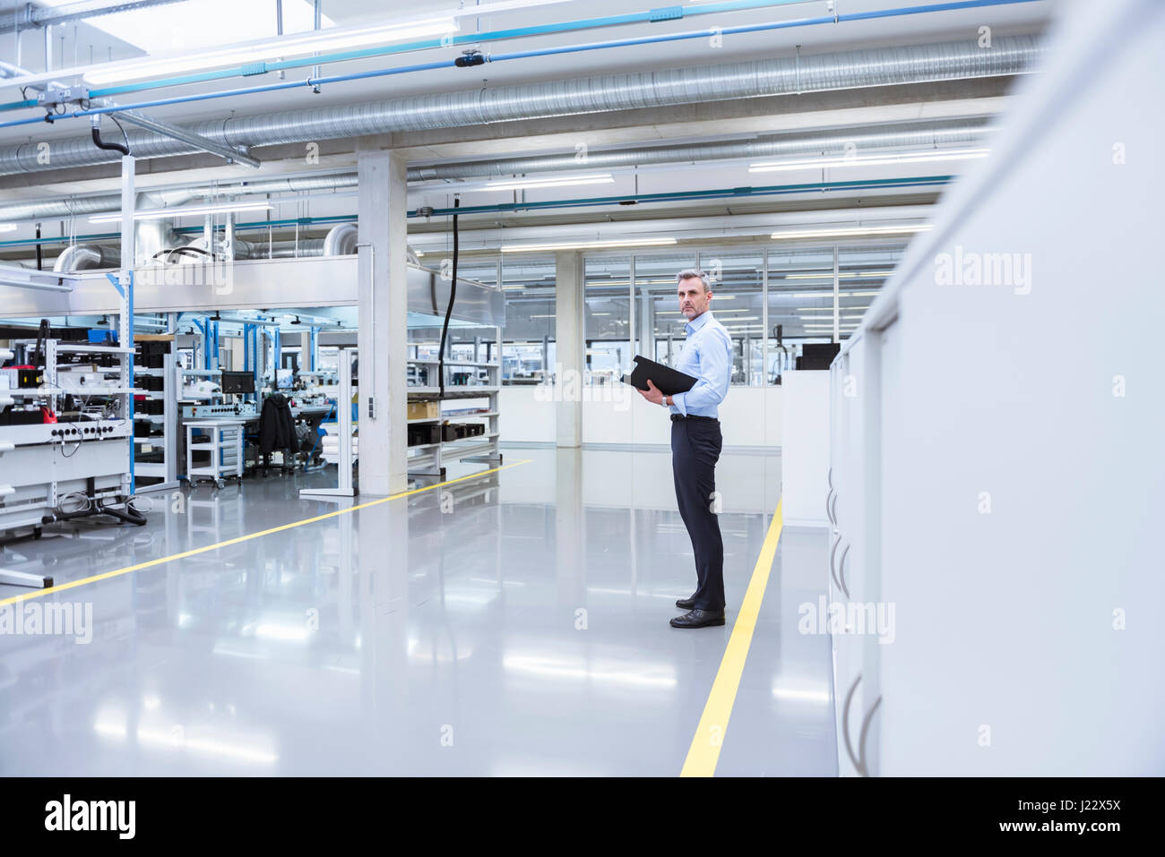 Manager with files walking through factory Stock Photo - Alamy