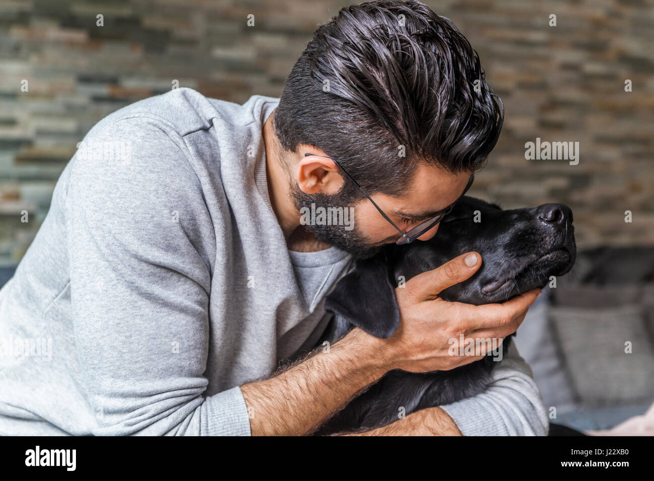 Man cuddling with his dog at home Stock Photo - Alamy