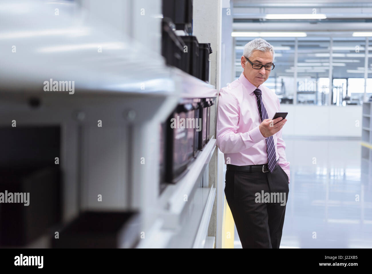 Manager on shop floor of a factory using smart phone Stock Photo - Alamy
