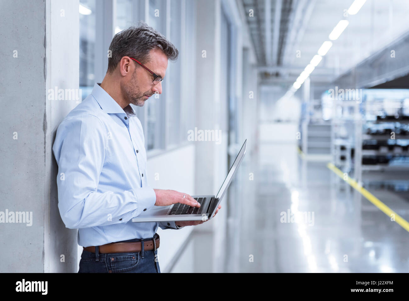 Manager on shop floor of factory using laptop Stock Photo - Alamy