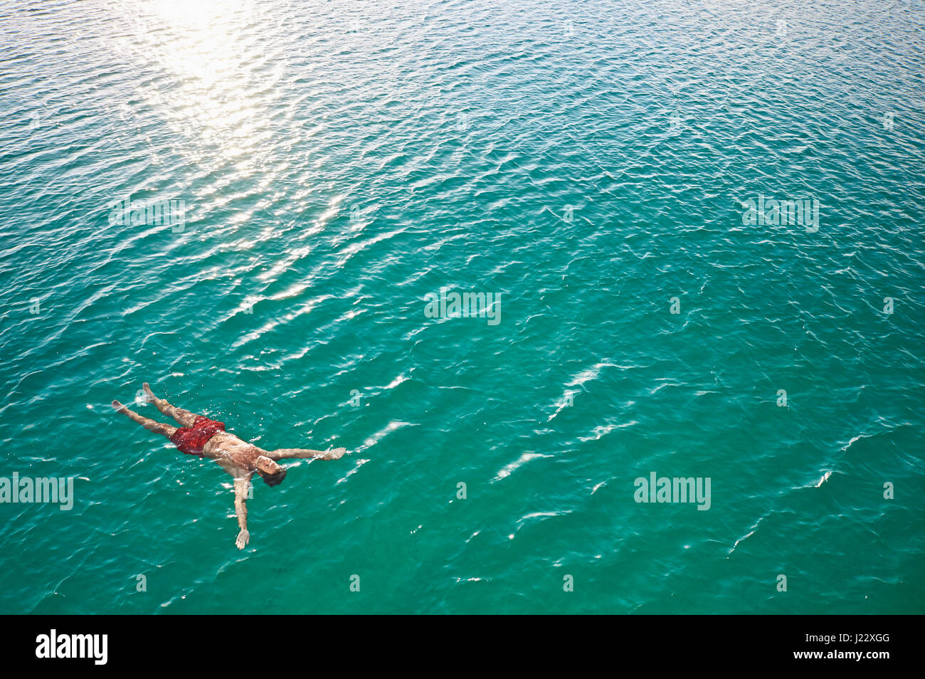 Mature man floating in emerald water Stock Photo - Alamy