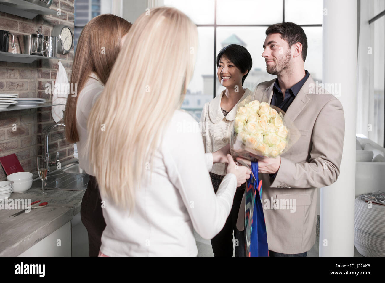 Friends gathered together in open plan kitchen Stock Photo - Alamy