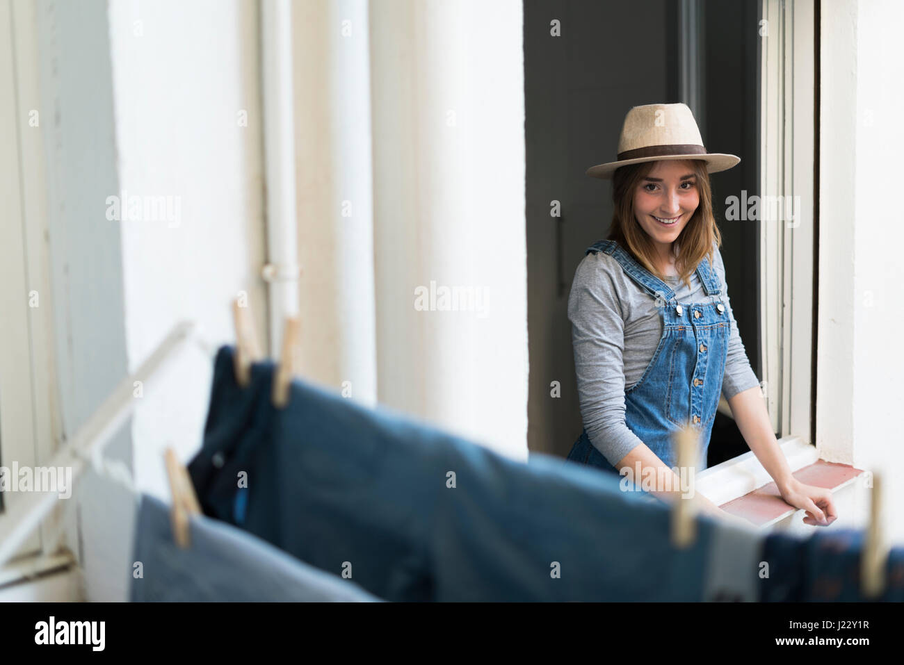 Smiling young woman looking out of window Stock Photo - Alamy