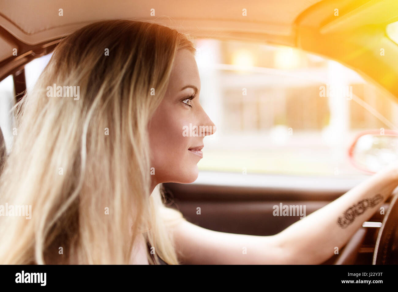 Smiling blond woman driving car Stock Photo - Alamy