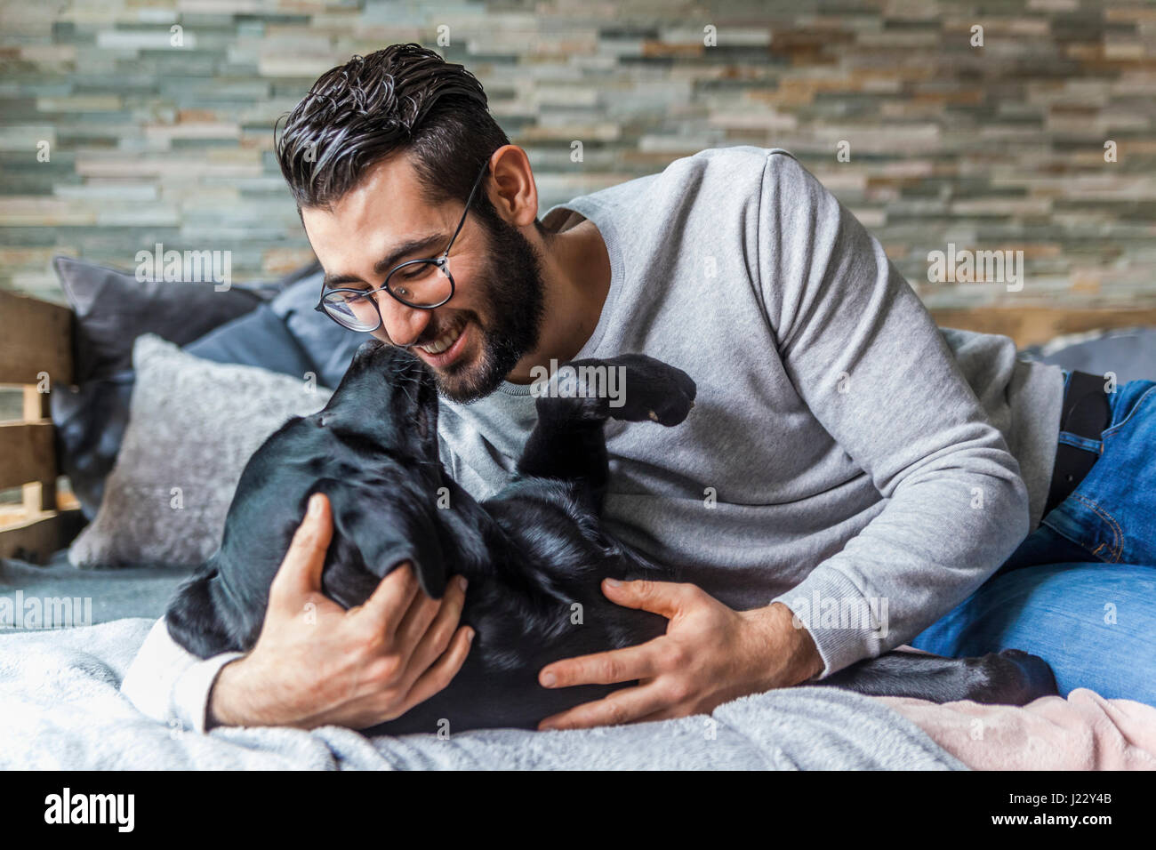 Smiling man cuddling with his dog on the couch at home Stock Photo - Alamy