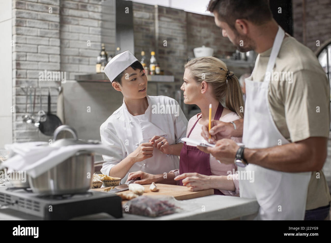 Participants and female chef cooking in cooking class Stock Photo - Alamy