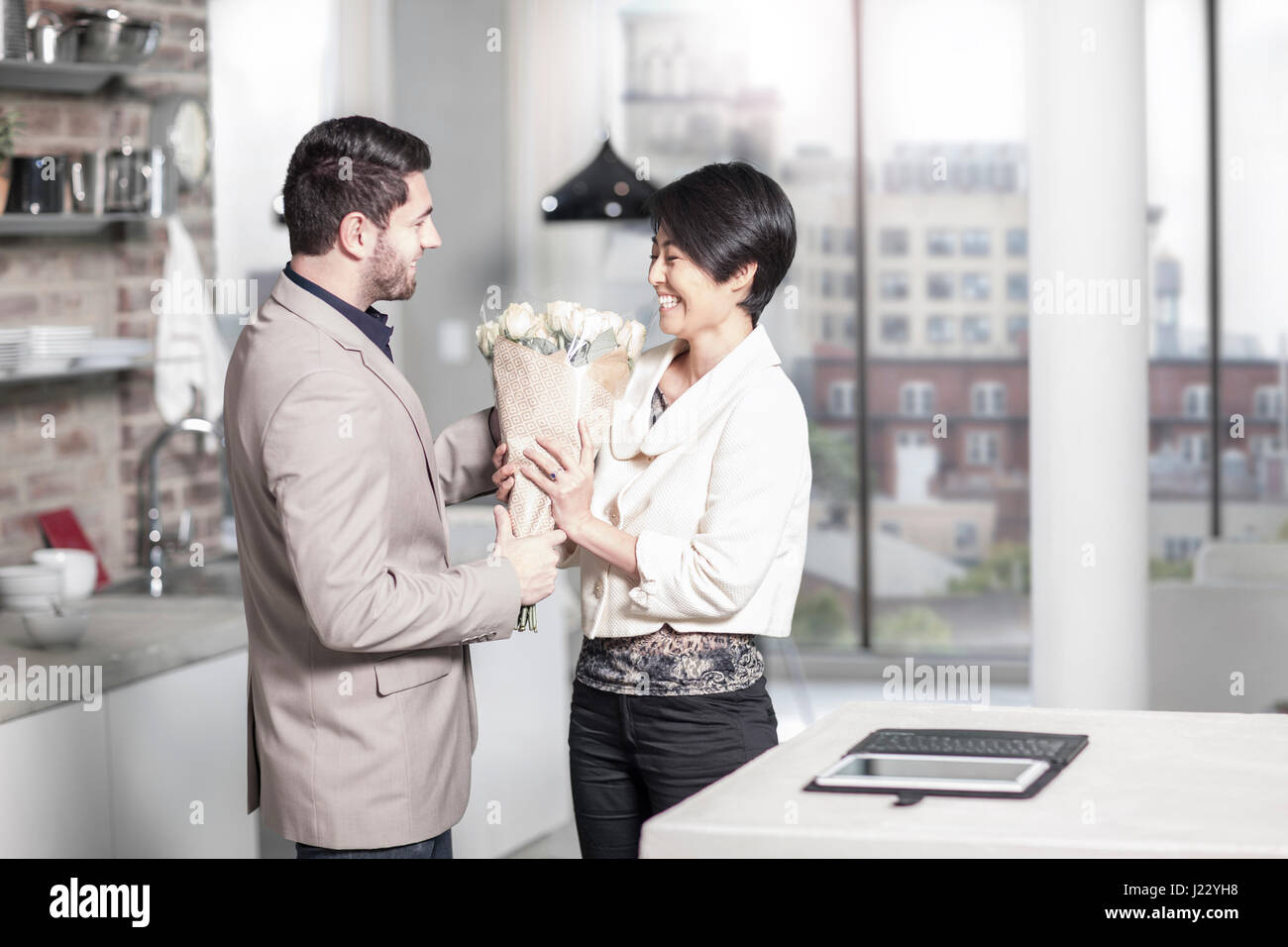 Man handing over roses to woman at home Stock Photo - Alamy