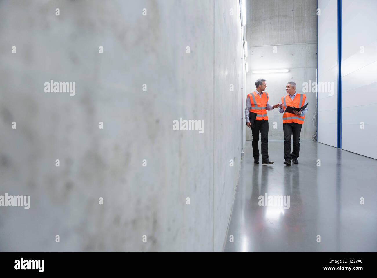 Two colleagues wearing safety vests talking Stock Photo - Alamy