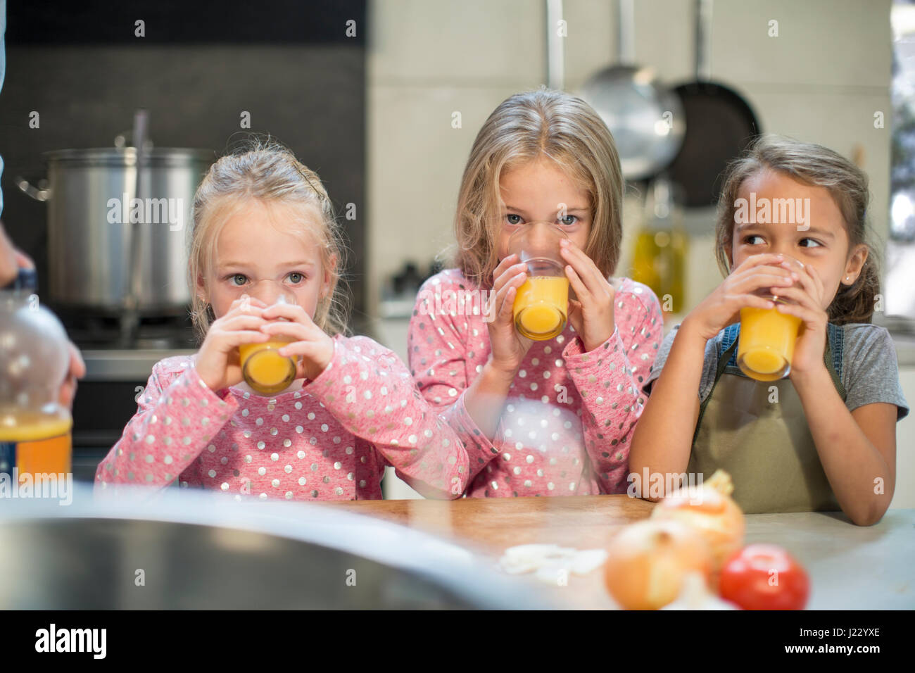 Girls drinking juice in kitchen Stock Photo - Alamy