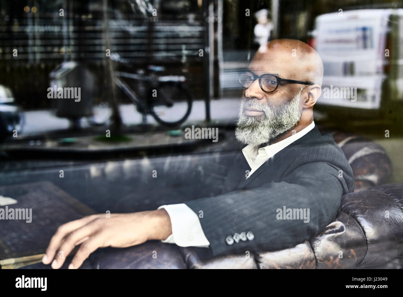 Mature businessman sitting in armchair, thinking Stock Photo - Alamy