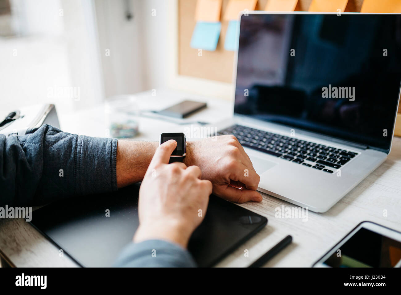 Man using smartwatch at desk Stock Photo - Alamy