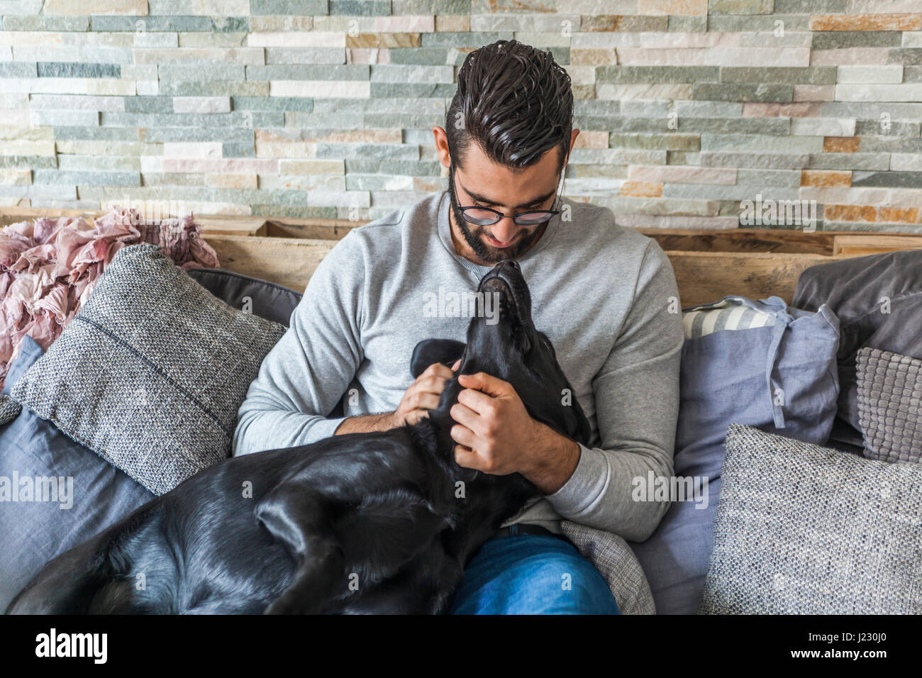 Man cuddling with his dog on the couch at home Stock Photo - Alamy