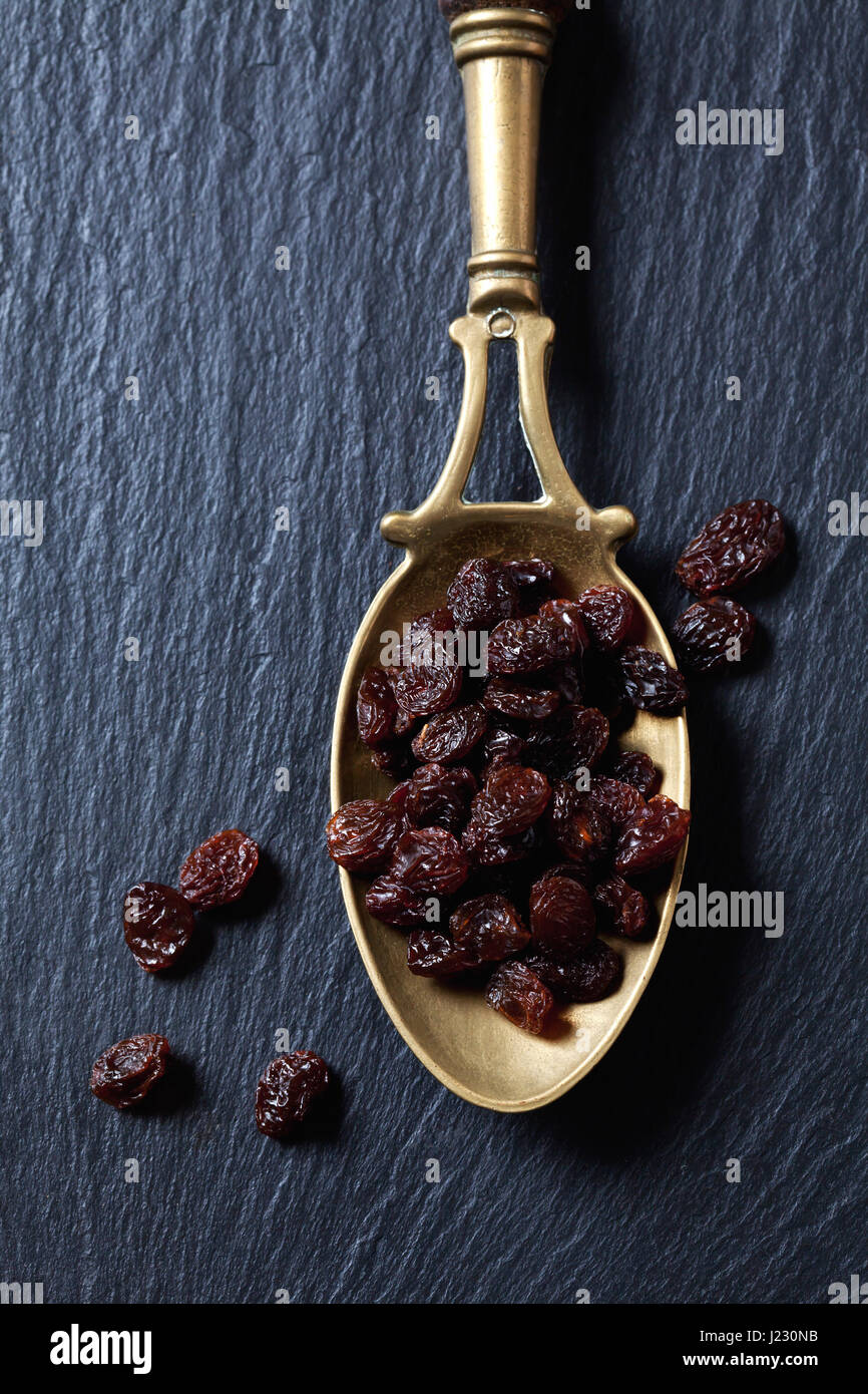 Raisins on brass spoon and slate Stock Photo - Alamy
