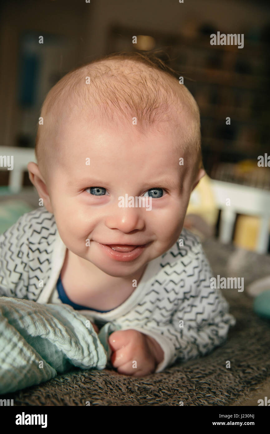Happy three-month-old baby looking up and smiling at something in his ...