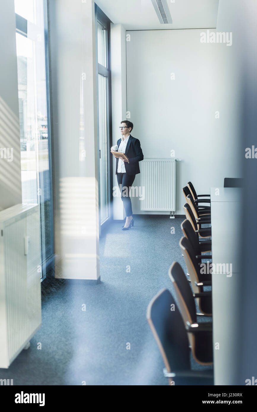 Businesswoman looking out of office window Stock Photo - Alamy