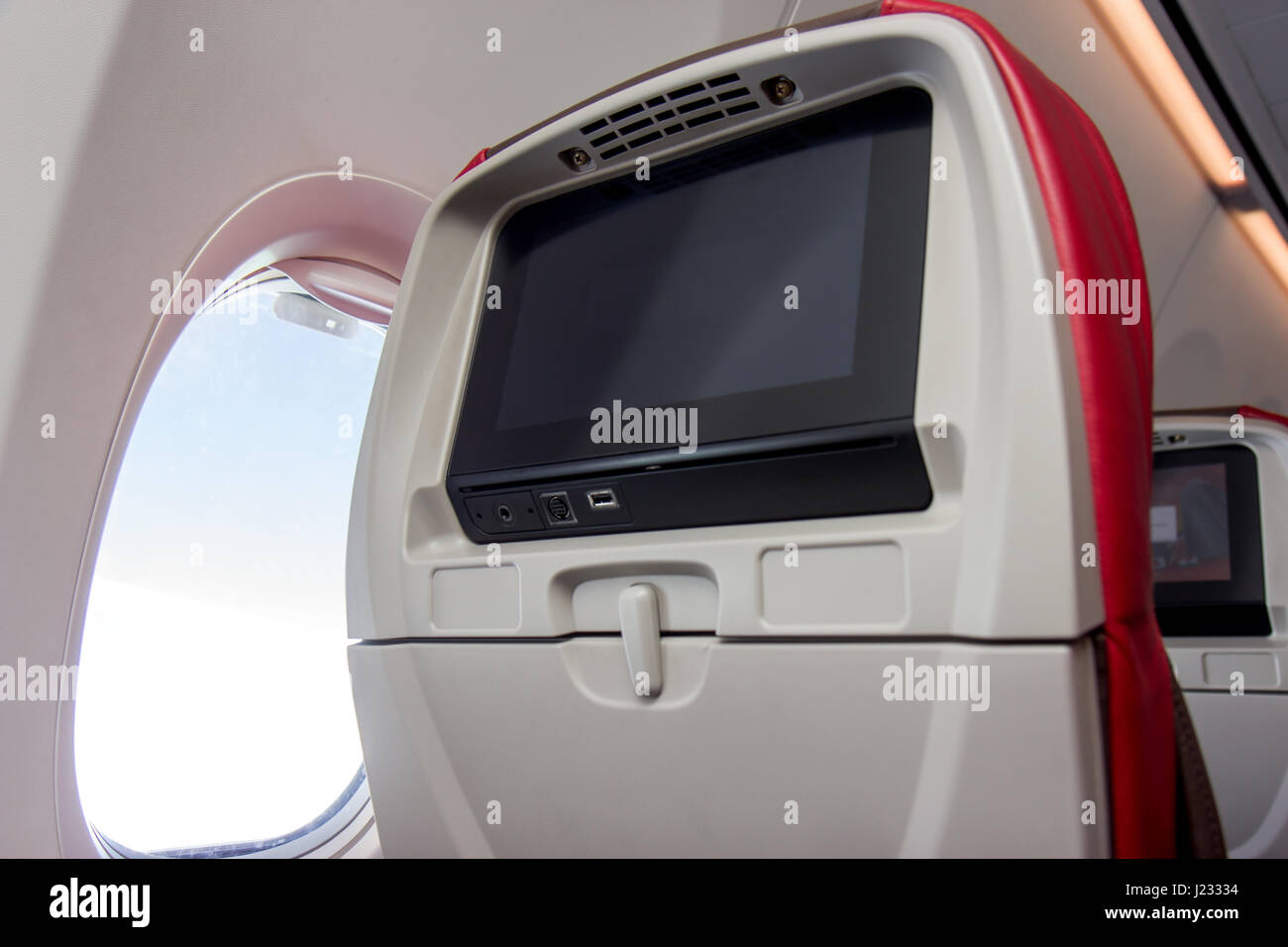 back of seat with a monitor beside the window of a flying airplane ...