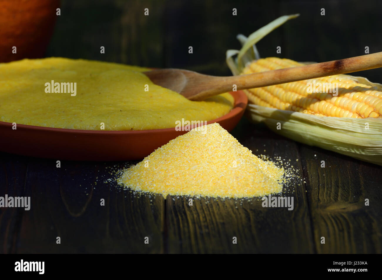 Heap of ground corn, polenta and a corn cob placed on wooden table in ...