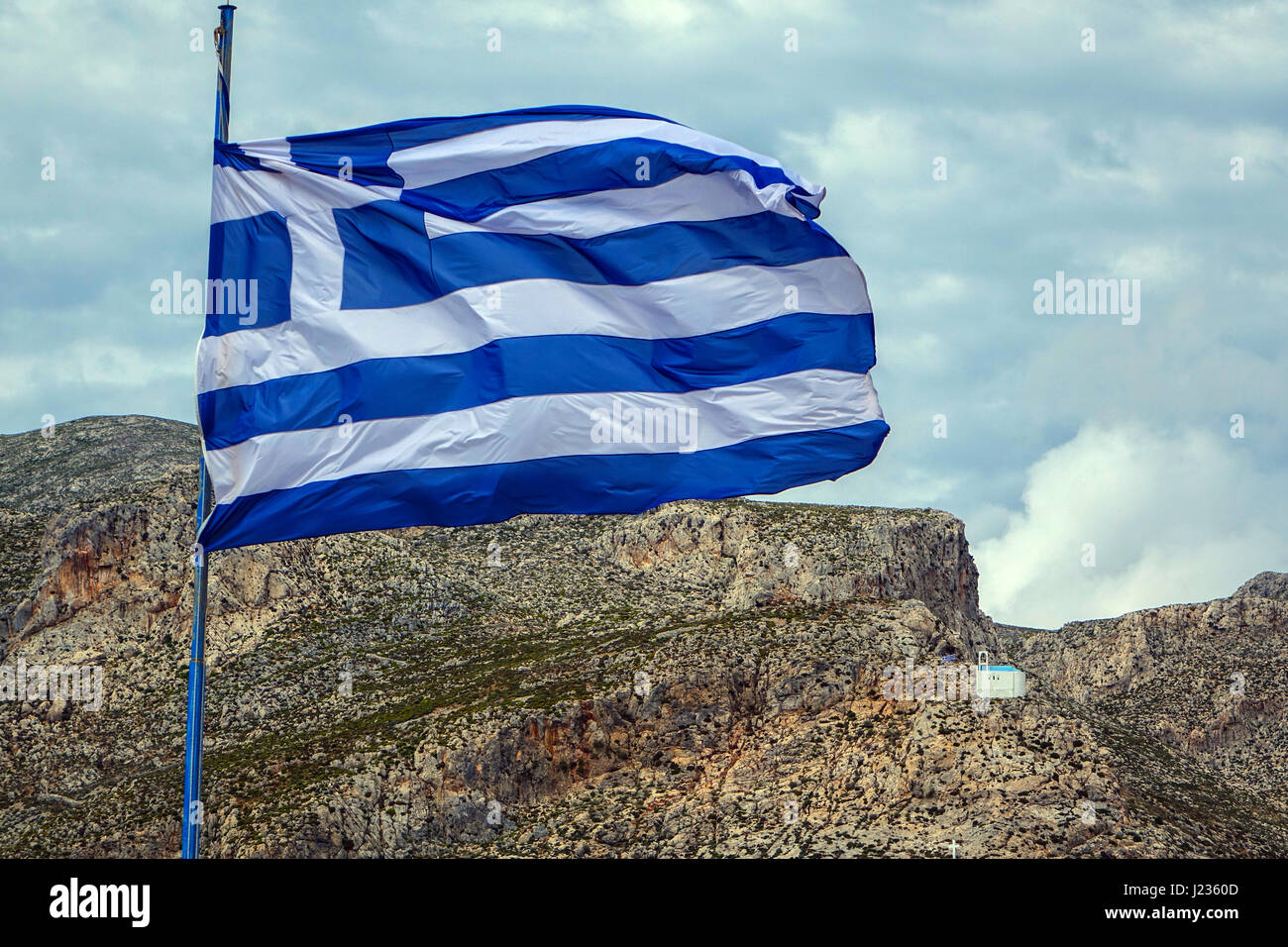 Large Greek flag flying agains sky with tiny chapel on hillside Stock ...