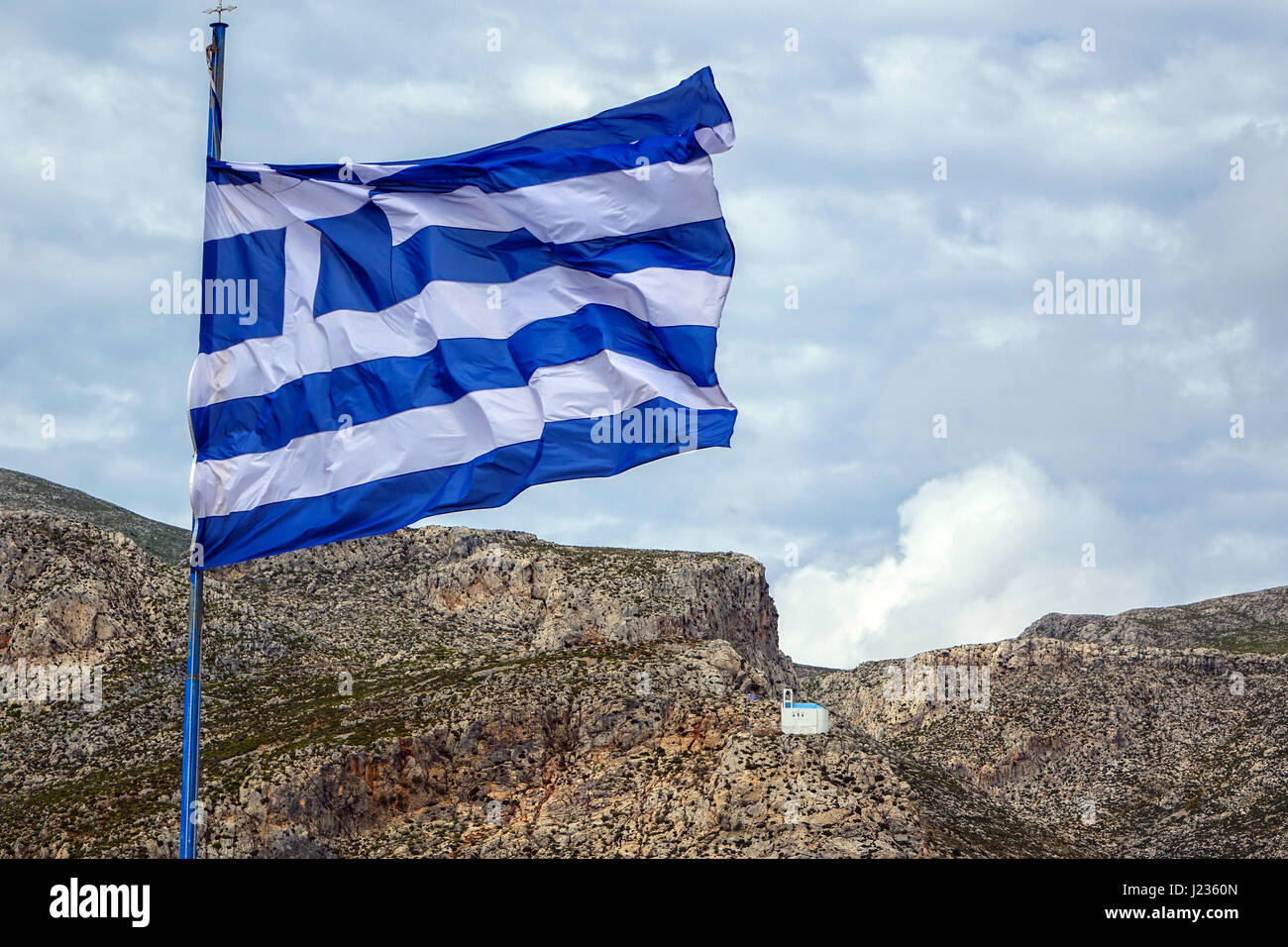 Large Greek flag flying agains sky with tiny chapel on hillside Stock ...