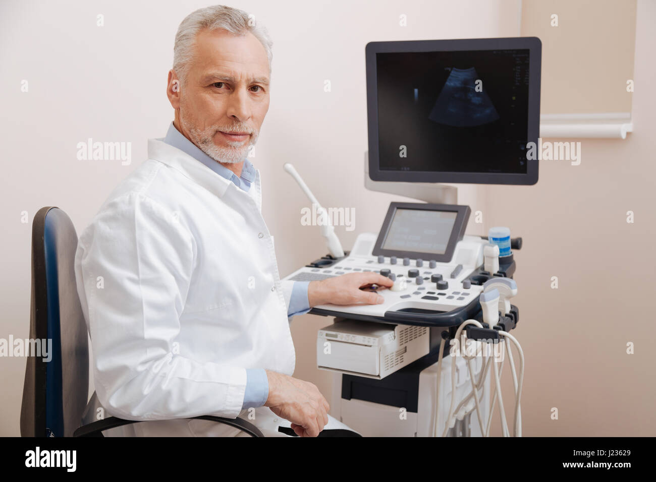 Bearded aged doctor using medical equipment in the hospital Stock Photo ...