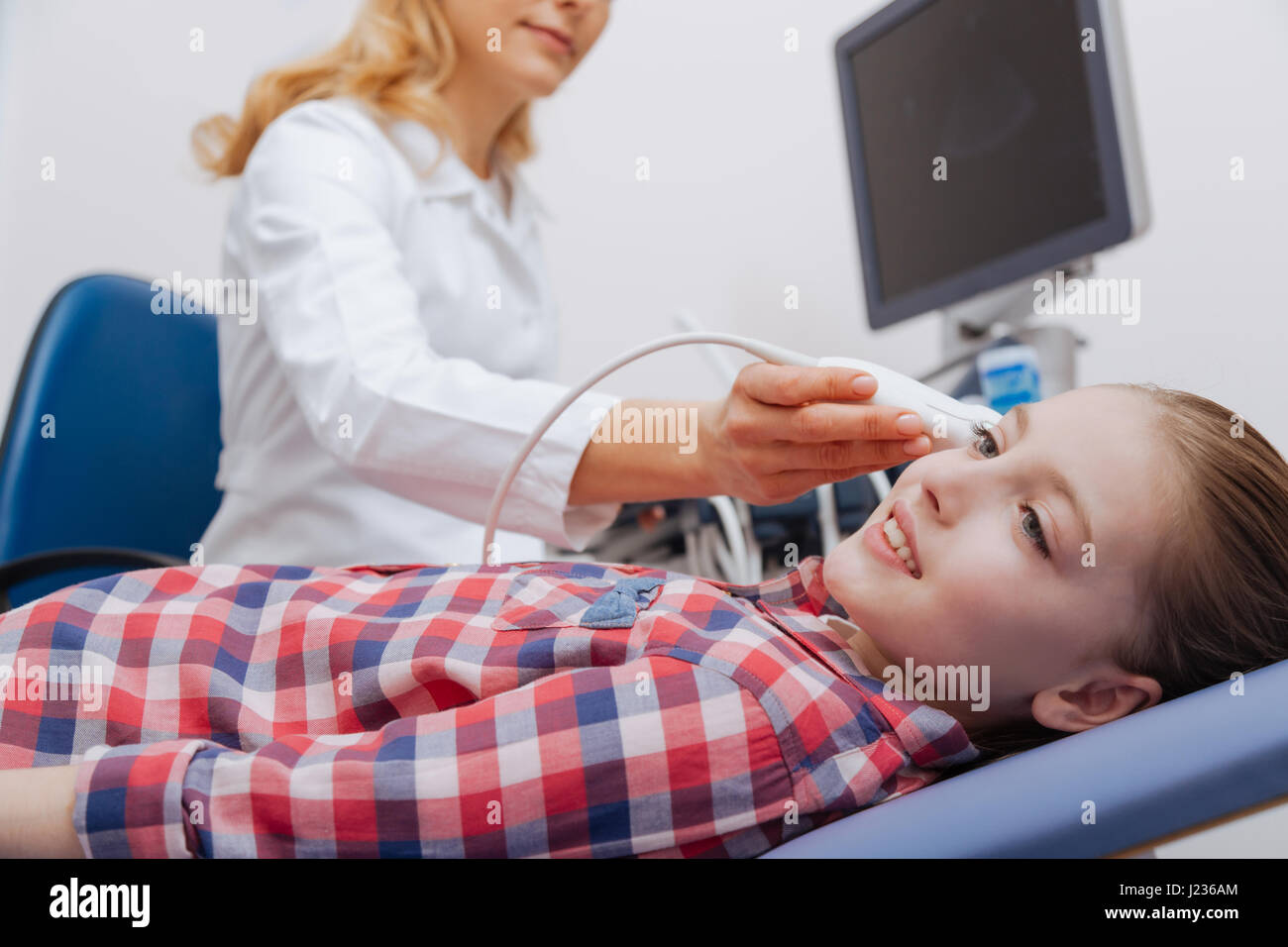 Skillful young doctor providing ultrasonic head examination in the ...